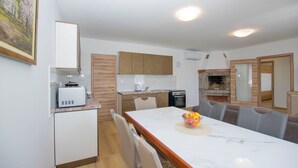 Uma cozinha moderna com área de refeições, destacando bancada de mármore, armários de madeira e forno embutido.