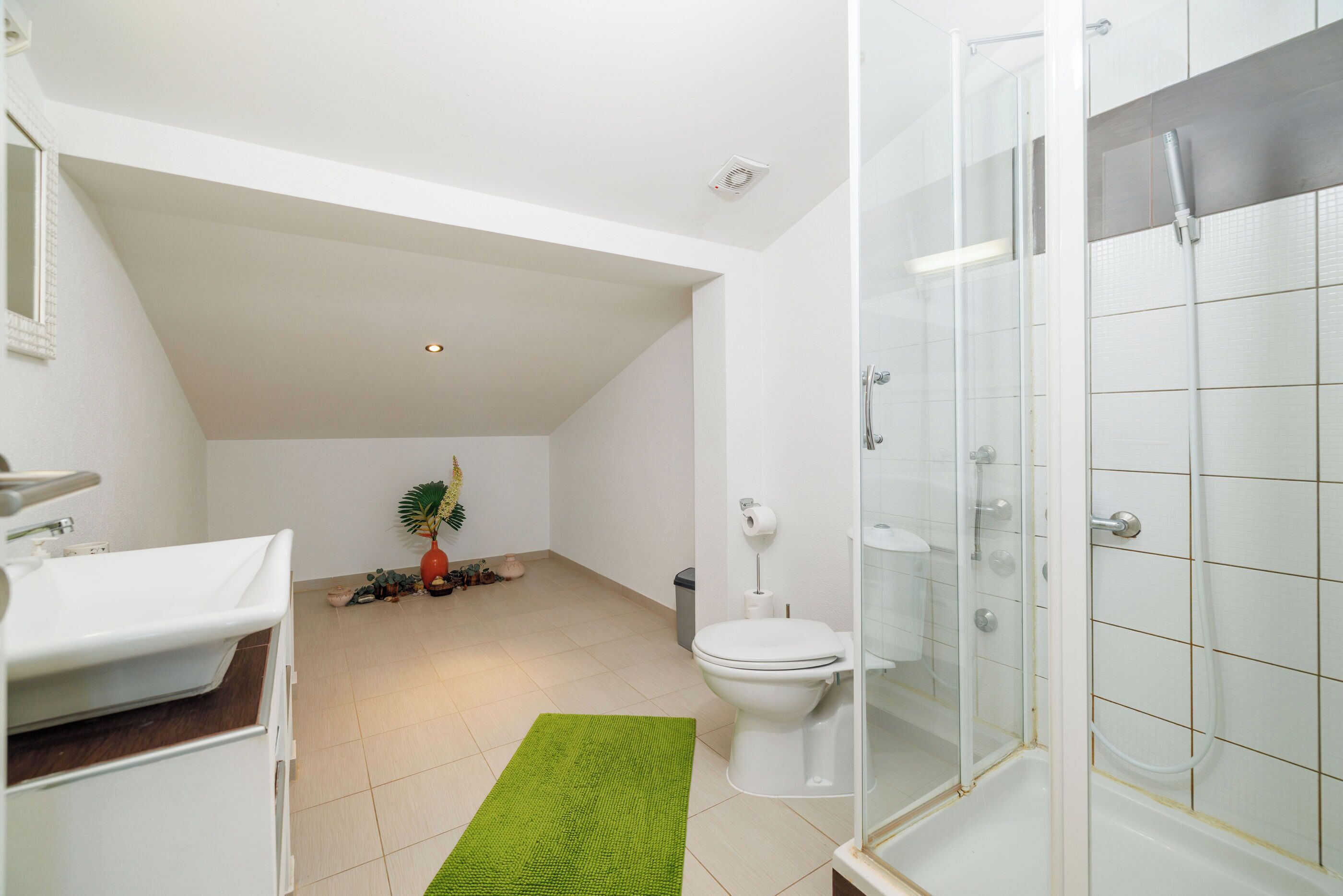 Casa de banho moderna com chuveiro, sanita e lavatório.