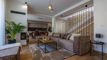 Uma sala de estar moderna com sofá, mesa de centro e escada com guarda-corpo de pedra.