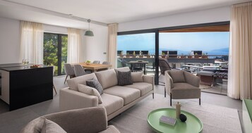 Uma sala de estar moderna com um sofá, cadeiras, uma mesa de centro e vista para a varanda.