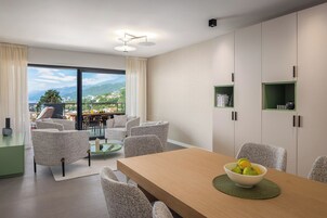 Um interior moderno com área de refeições, sofás e vista para o exterior.