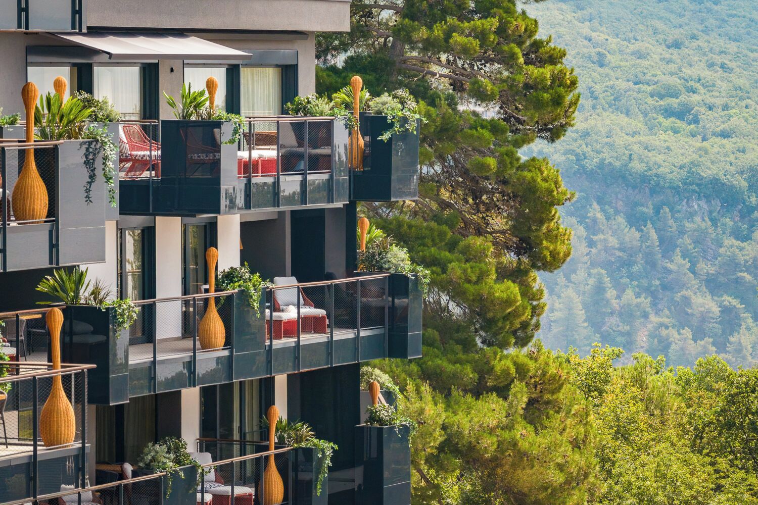 Um edifício com várias andares, varandas, área de estar ao ar livre e vegetação exuberante.