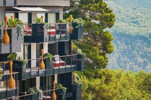 Um edifício com várias andares, varandas, área de estar ao ar livre e vegetação exuberante.