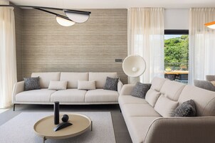 Uma sala de estar moderna com um sofá, uma mesa de centro redonda e um abajur.