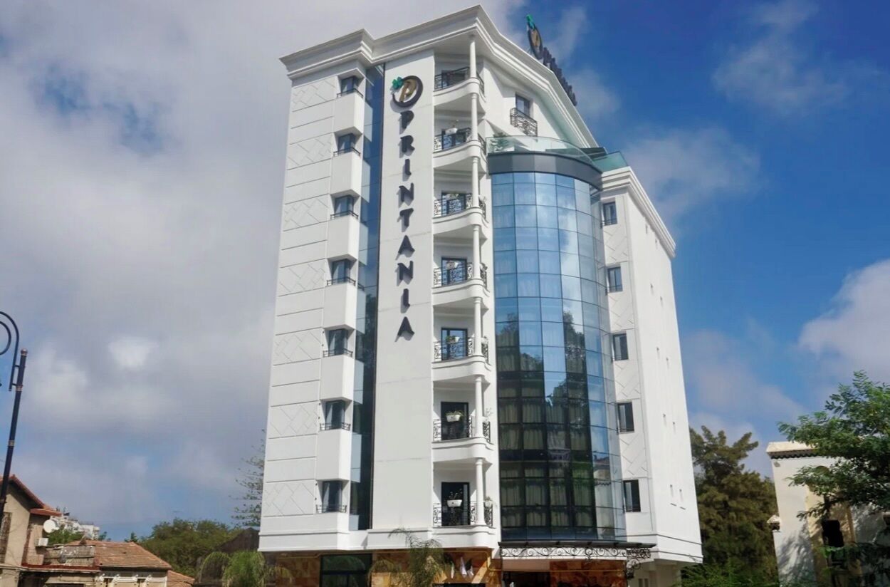 Um hotel moderno com uma placa de destaque “Printania”, várias varandas e fachada de vidro curva.