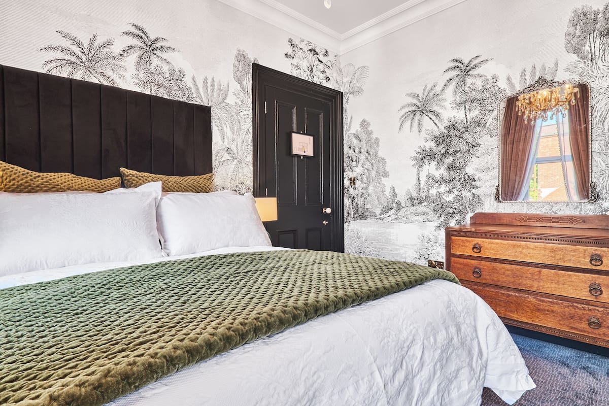 Quarto com cama, cômoda e porta.