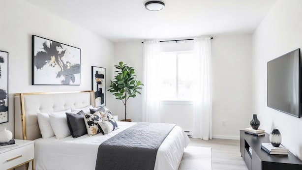 Um quarto moderno com uma cama grande, uma mesa de cabeceira, uma televisão e uma janela com cortinas.