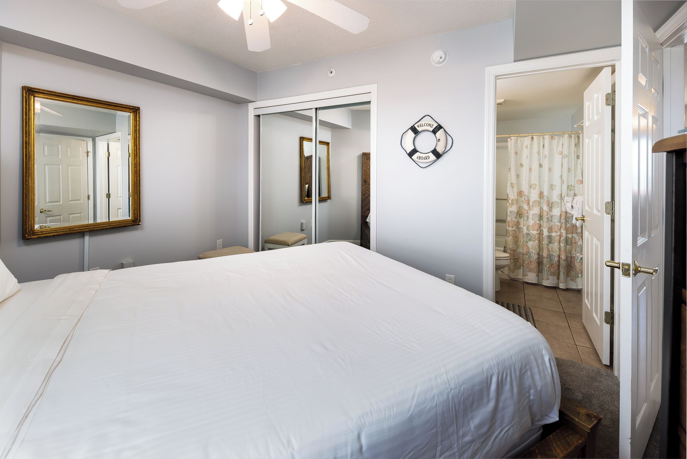 Quarto com cama grande, espelho, guarda-roupa e porta para um banheiro.