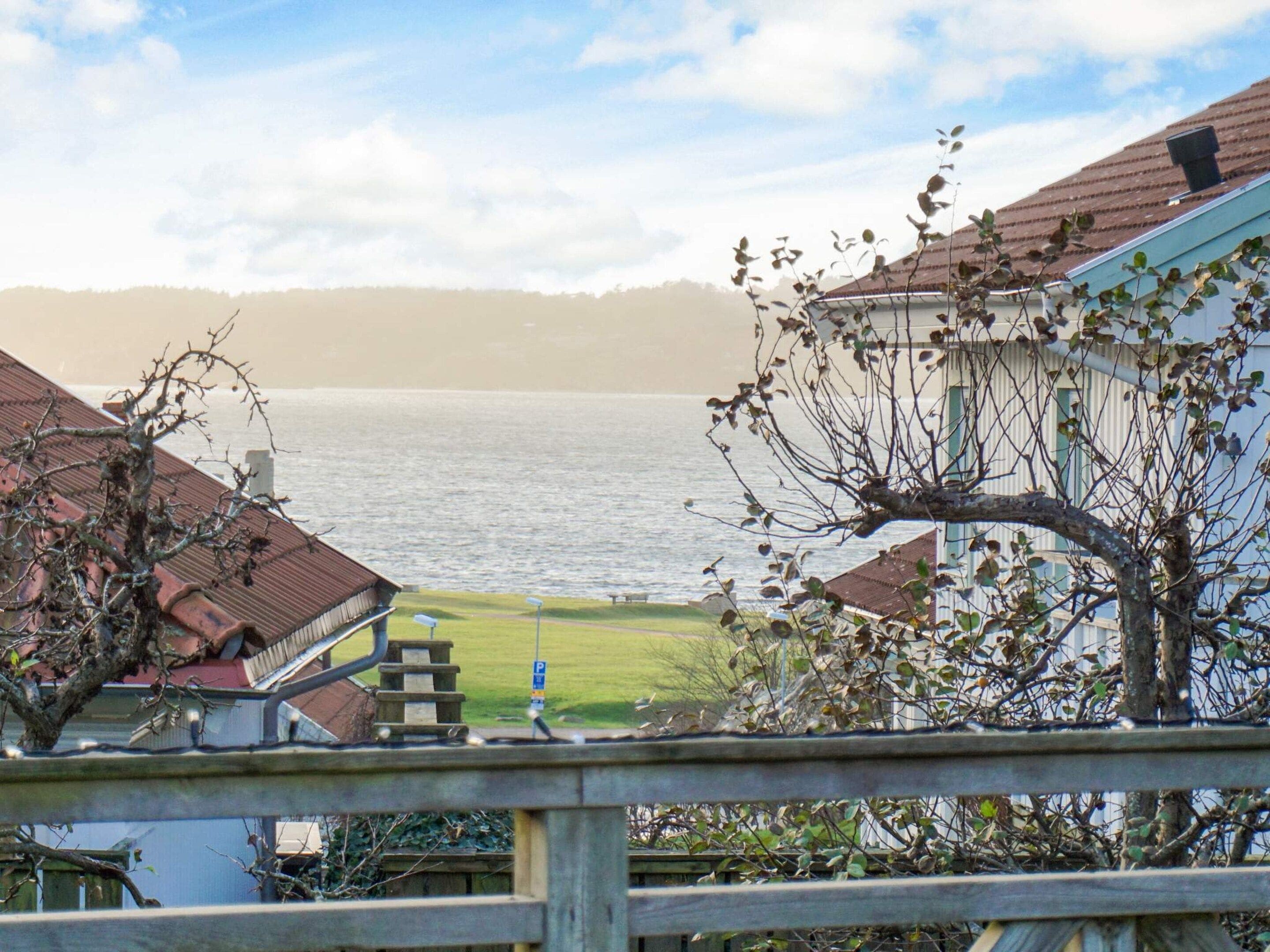 Área residencial com vista para um corpo d'água, um campo gramado e um edifício com telhado vermelho.
