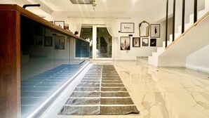 Interior moderno com guarda-corpo de vidro, piso de mármore e escada com relógio.