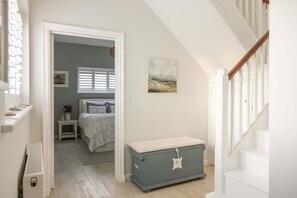 Quarto com cama, mesa de cabeceira, cômoda e um quadro na parede.
