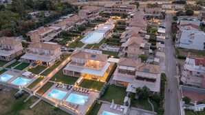 Vista aérea de uma área residencial com várias casas, uma piscina e um gramado bem cuidado.
