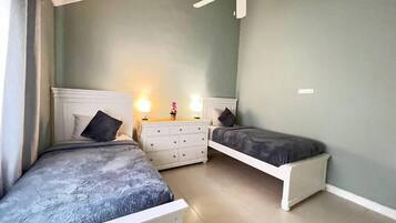Quarto com duas camas, um ventilador de teto e luminárias de cabeceira.