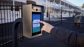 Uma pessoa usando um celular para interagir com um quiosque de segurança.