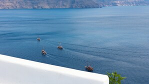 Vista costeira com barcos na água e montanhas ao fundo.