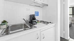 Cozinha moderna com pias de aço inoxidável, máquina de café e placa indicando área para fumantes.