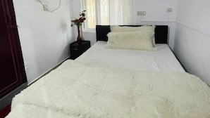 Quarto com cama, mesa de cabeceira, janela com cortinas e ar condicionado na parede.