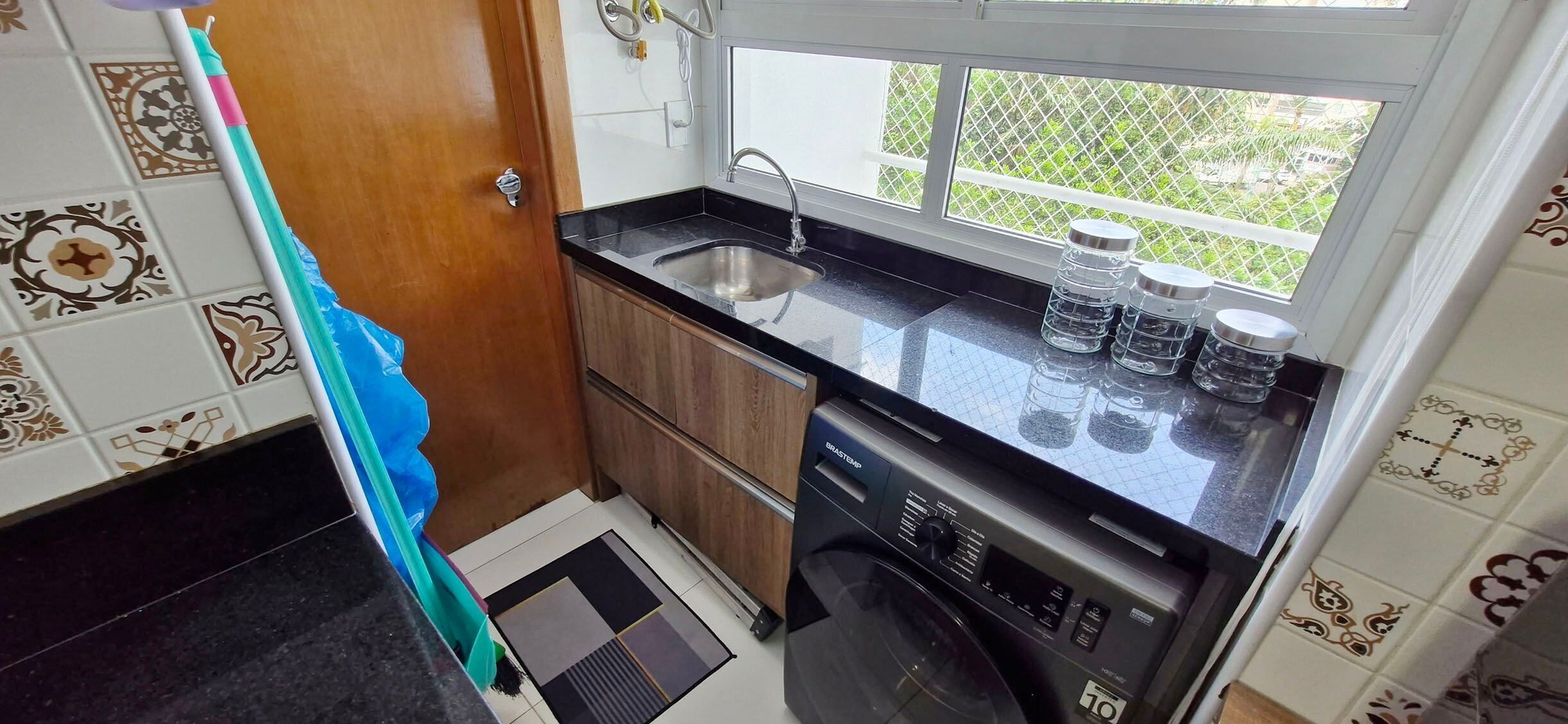 Cozinha compacta com pia, bancada e máquina de lavar.
