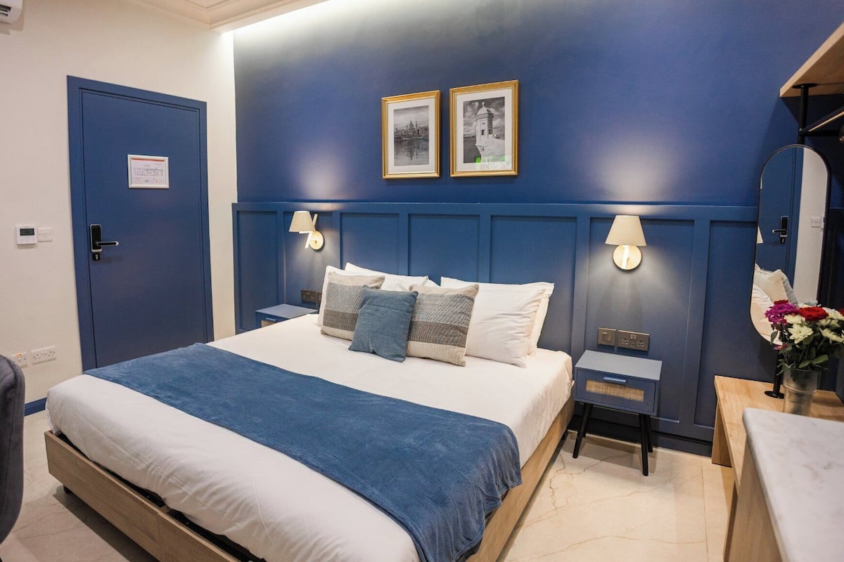 Quarto de hotel moderno com uma cama grande, mesas de cabeceira, uma escrivaninha e uma cadeira.