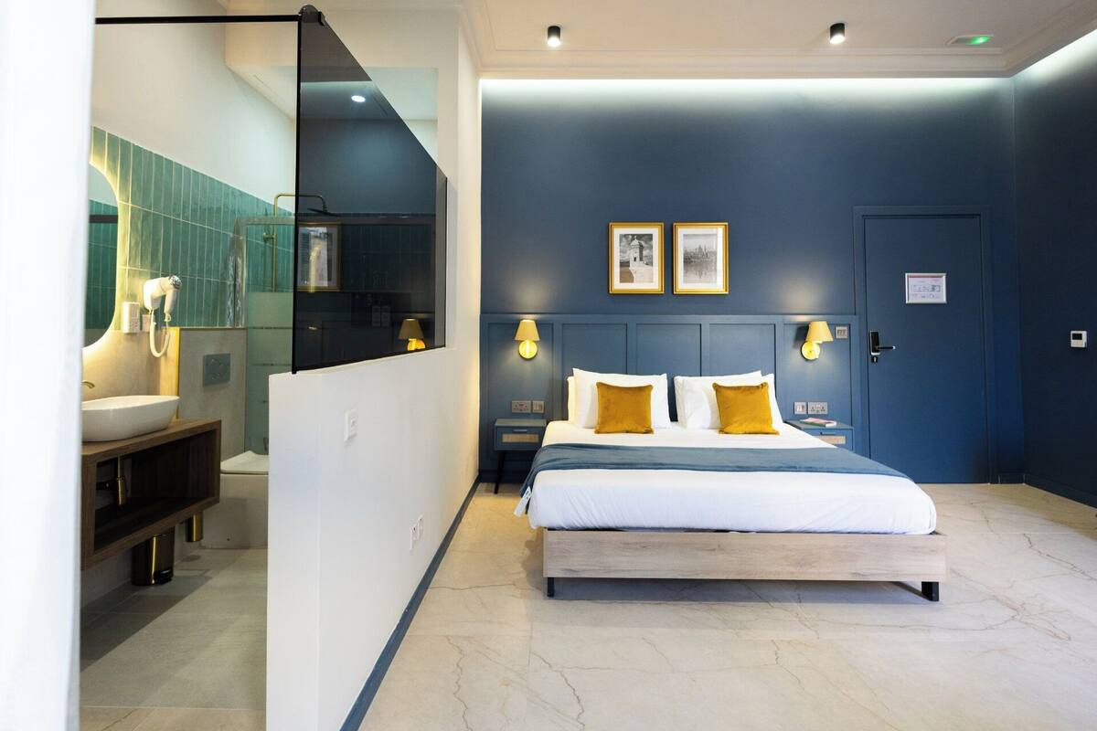 Quarto moderno com cama, mesas de cabeceira, espelho e porta.