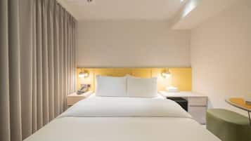 Quarto de hotel com uma cama grande, luminárias de cabeceira, uma escrivaninha e uma cadeira.