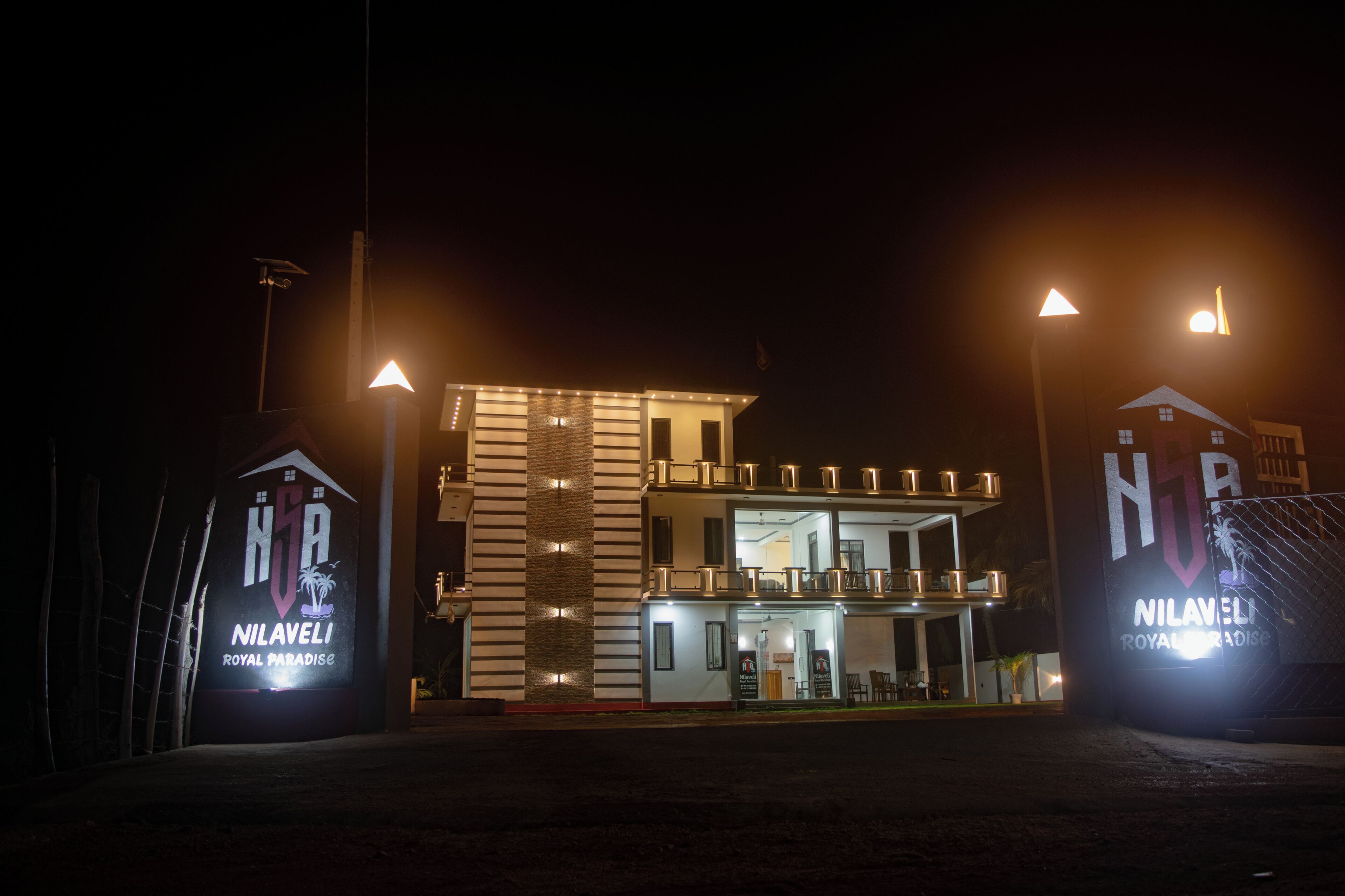 Um hotel com design moderno, destacando uma entrada imponente, uma varanda e sinalização iluminada.