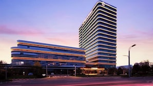 Um hotel moderno com fachada curva e uma torre alta e retangular.