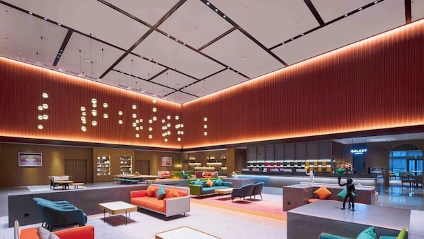 Um lobby espaçoso com assentos modernos, um café Galaxy e uma grande tela digital.