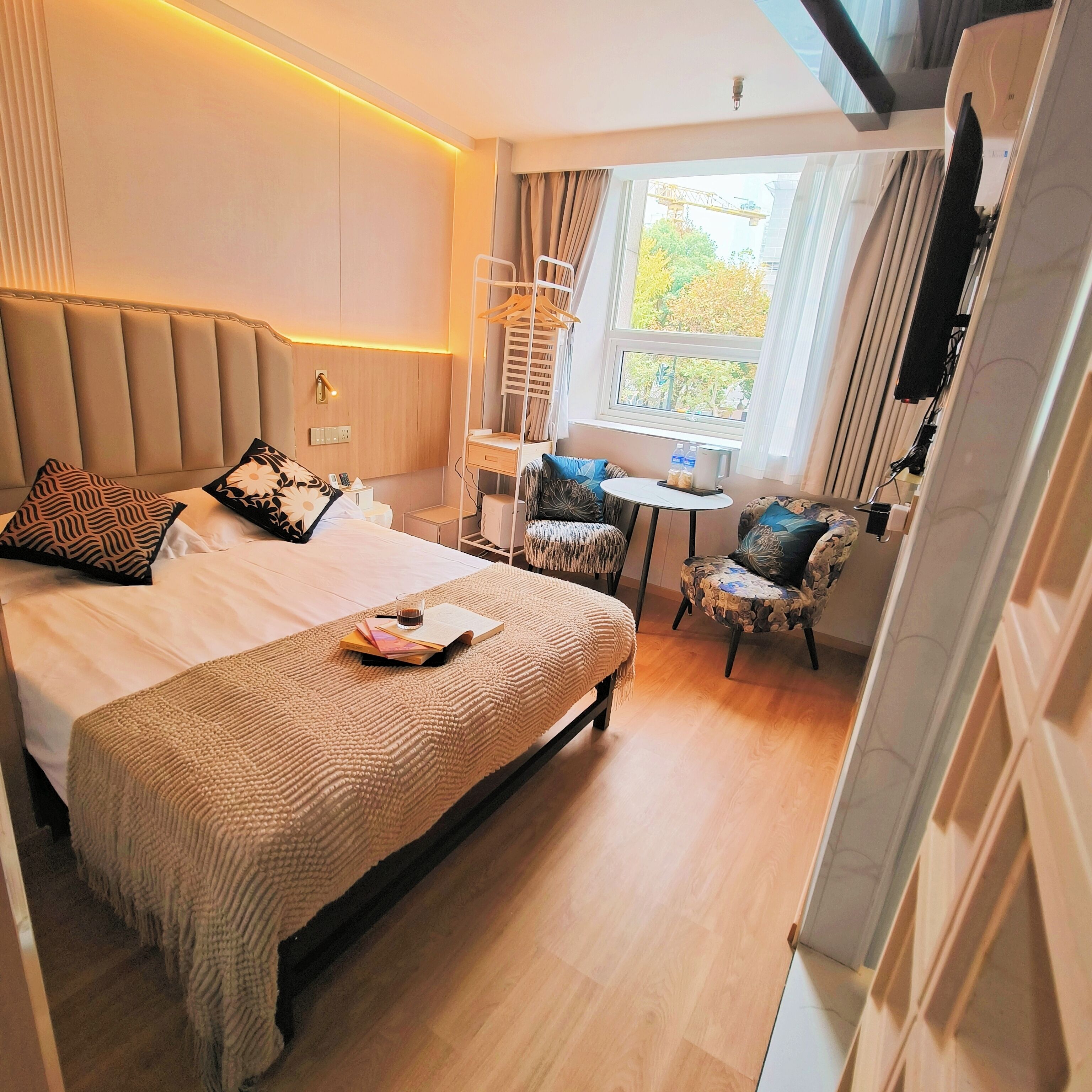 Quarto de hotel com uma cama grande, uma mesinha e um espaço de estar com cadeiras.
