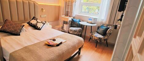 Quarto de hotel com uma cama grande, uma mesinha e um espaço de estar com cadeiras.