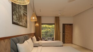 Quarto de hotel moderno com uma cama grande, vista para o verde e uma varanda.