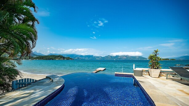 Uma piscina com vista para o mar e montanhas.