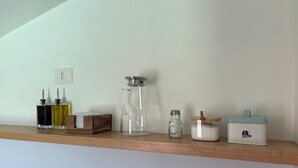 Uma prateleira com diversos recipientes, incluindo um jarro de vidro, uma garrafa pequena e um recipiente branco com tampa.