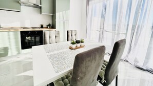 Uma cozinha moderna com área de jantar, incluindo uma mesa com cadeiras e uma janela com cortinas.