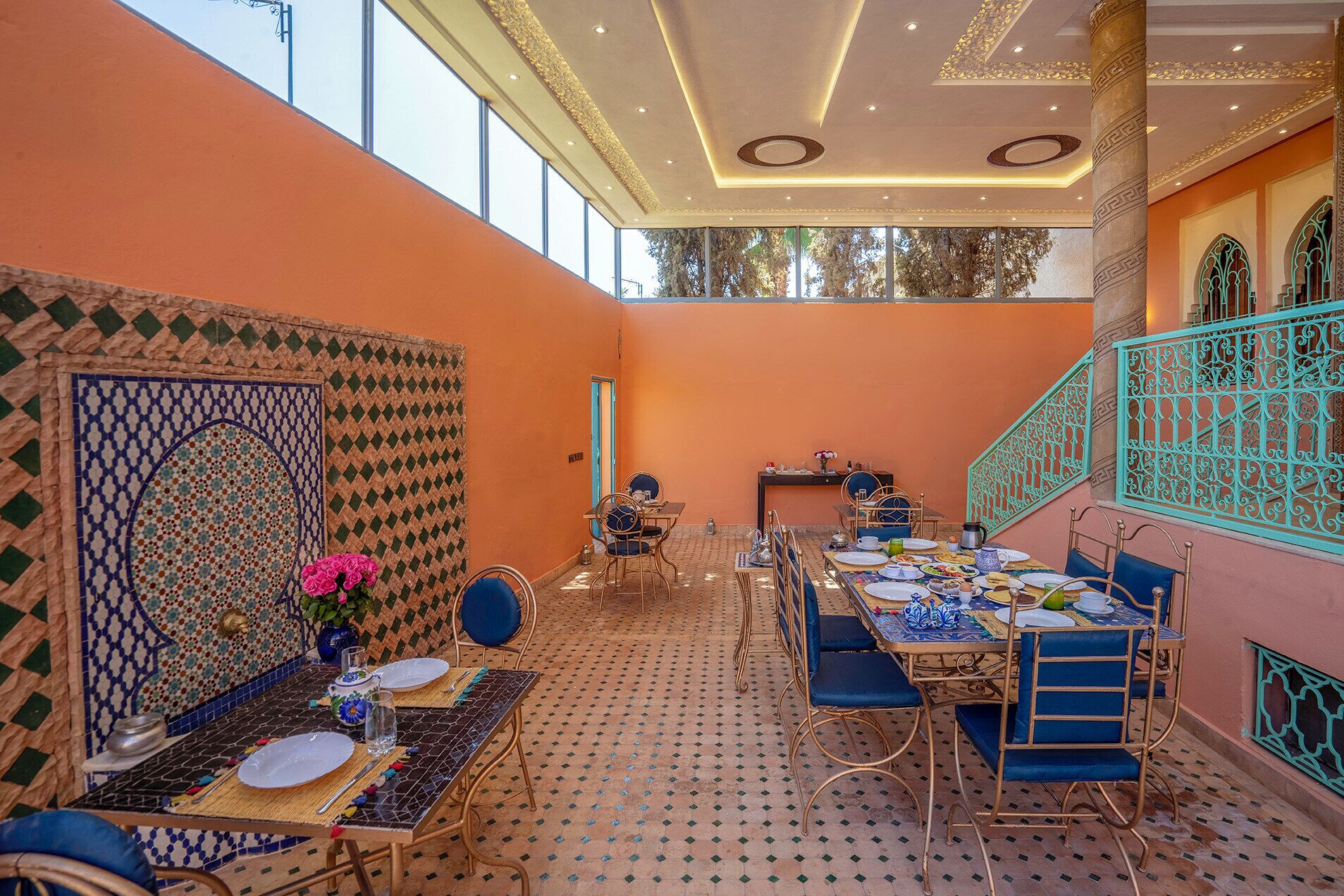 Uma sala de jantar com teto alto, paredes com padrão e escada com grades decorativas.