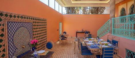 Uma sala de jantar com teto alto, paredes com padrão e escada com grades decorativas.