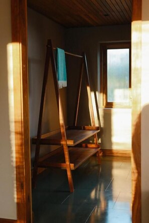 Um quarto com piso de madeira, uma janela com persianas e um balanço de madeira.