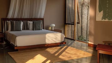 Um quarto com uma cama grande, uma mesa de cabeceira, uma luminária e vista pela janela.