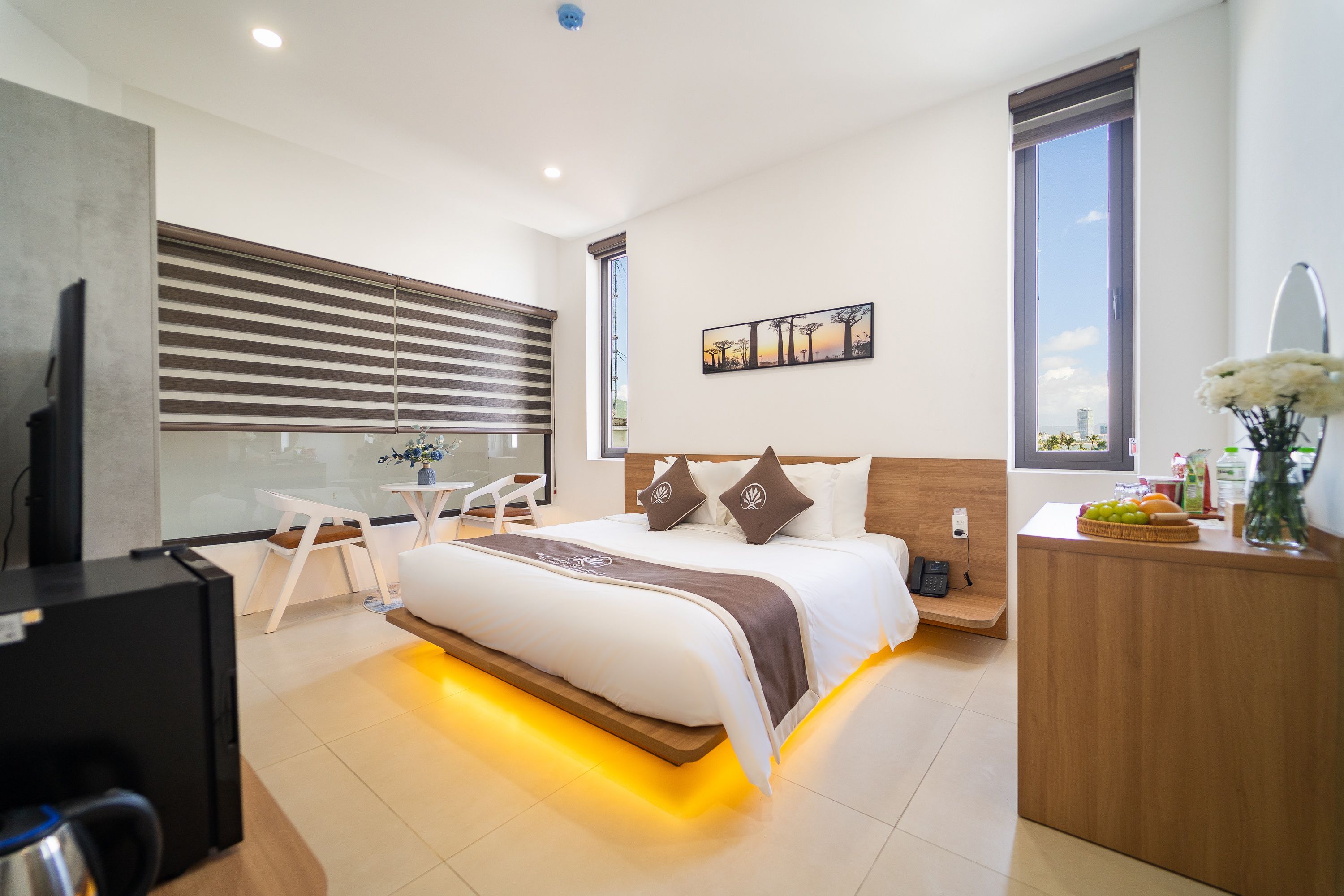 Quarto moderno com cama, mesa de cabeceira e uma grande janela.