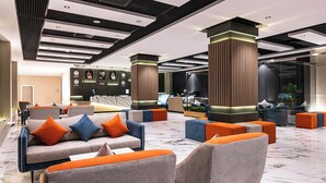 Um lobby moderno com áreas de estar, um balcão de recepção e uma parede com relógios e fotografias.