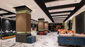 Um lobby moderno com áreas de estar, piso de mármore e teto com iluminação embutida.