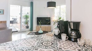 Uma sala de estar moderna com uma televisão grande, cafeteira e plantas em vasos.