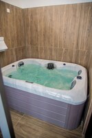 Um banheiro com parede de madeira, uma banheira com painel de controle e piso roxo.