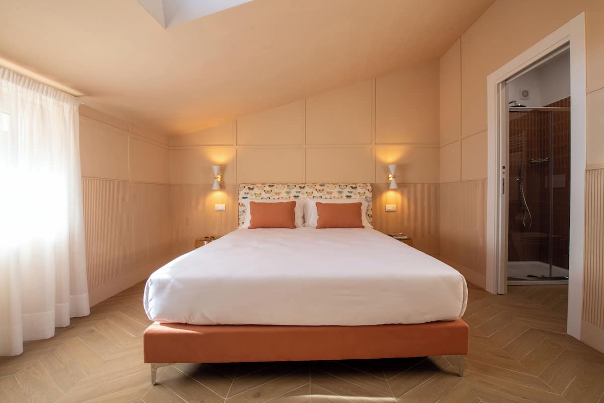 Quarto bem arrumado com uma cama grande, duas luminárias de cabeceira e uma área de chuveiro visível.