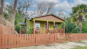Uma casa de dois andares com fachada verde e cerca de piquete marrom.
