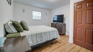 Quarto com cama, penteadeira, televisão e porta.
