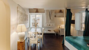 Quarto com mesa de jantar, cadeiras, abajur, cama e uma mesinha de cabeceira.