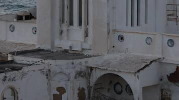 Um edifício branco com uma cúpula e uma cruz no topo, perto de um corpo d'água.