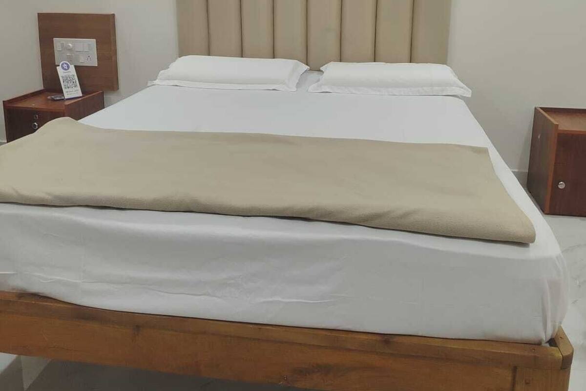 Uma cama de solteiro com estrutura de madeira e cabeceira com ripas verticais.