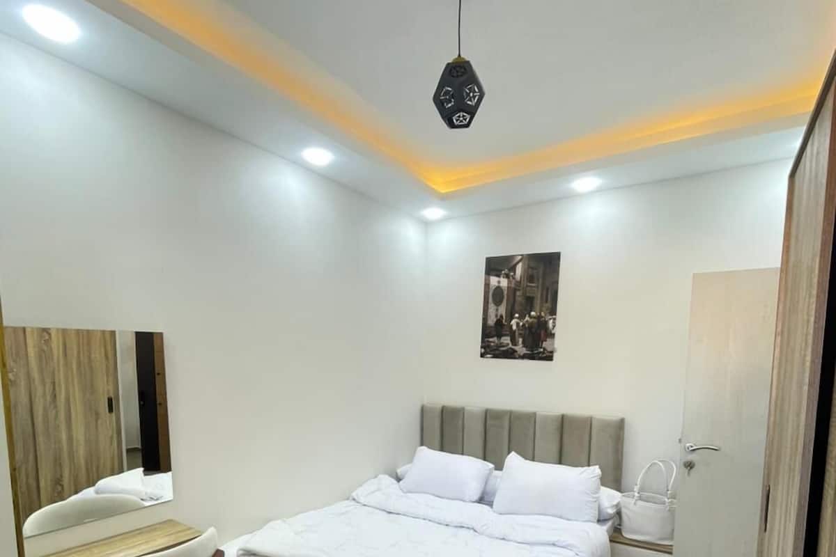 Quarto moderno com cama de madeira, escrivaninha e guarda-roupa.